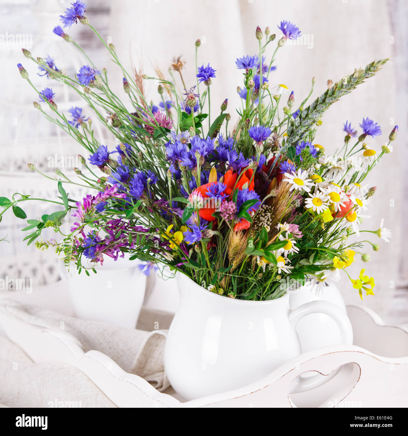 Wildflowers in white ceramic jug and cups on tray Stock Photo - Alamy