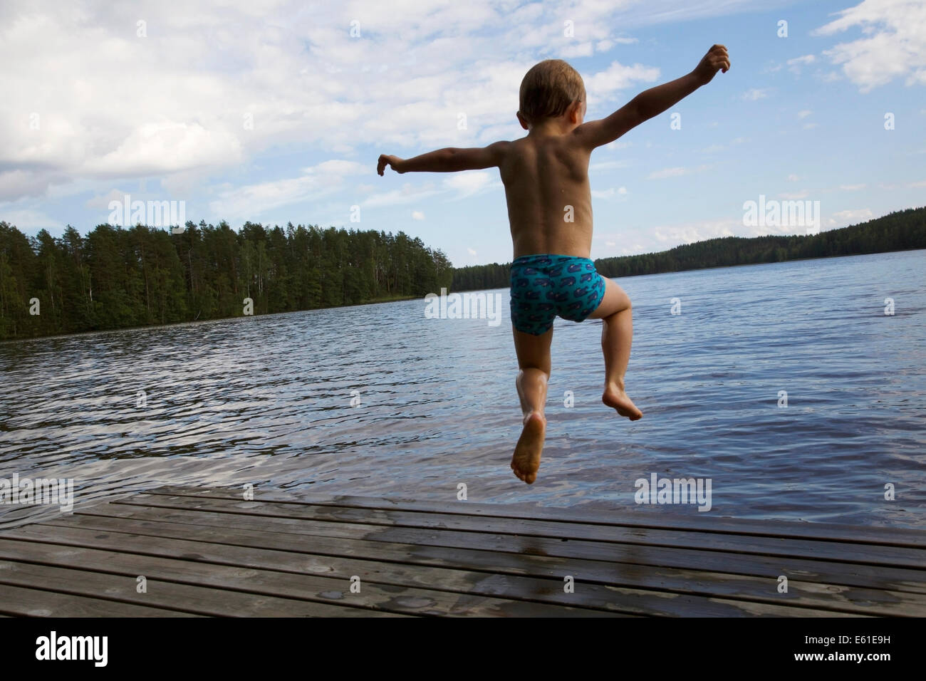 A boy jumping into water off the pier in summer in Finland Stock Photo ...