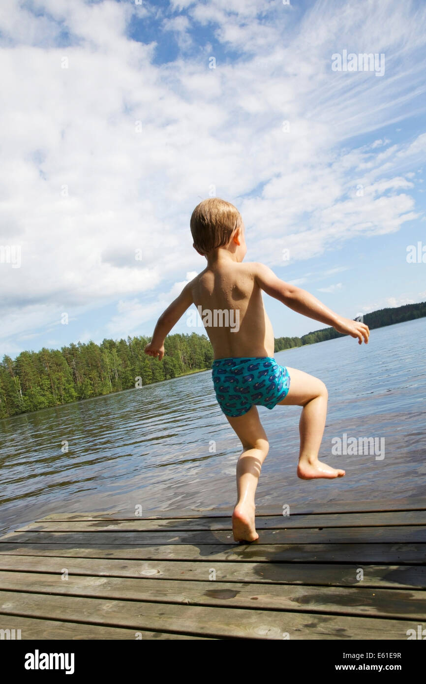 A boy jumping into water off the pier in summer in Finland Stock Photo ...