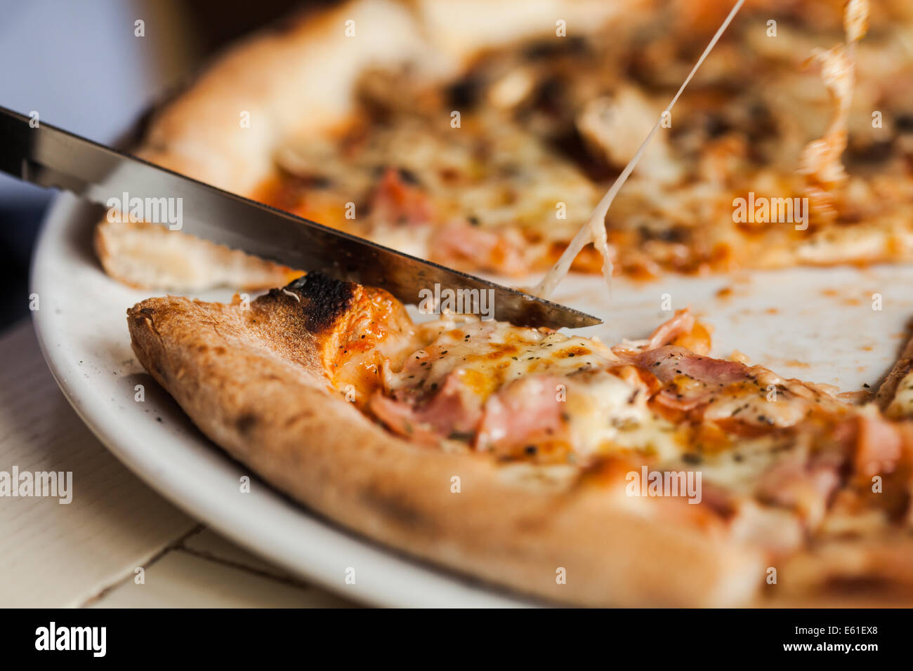 Man eats pizza. Close up pizza with fork and knife Stock Photo - Alamy