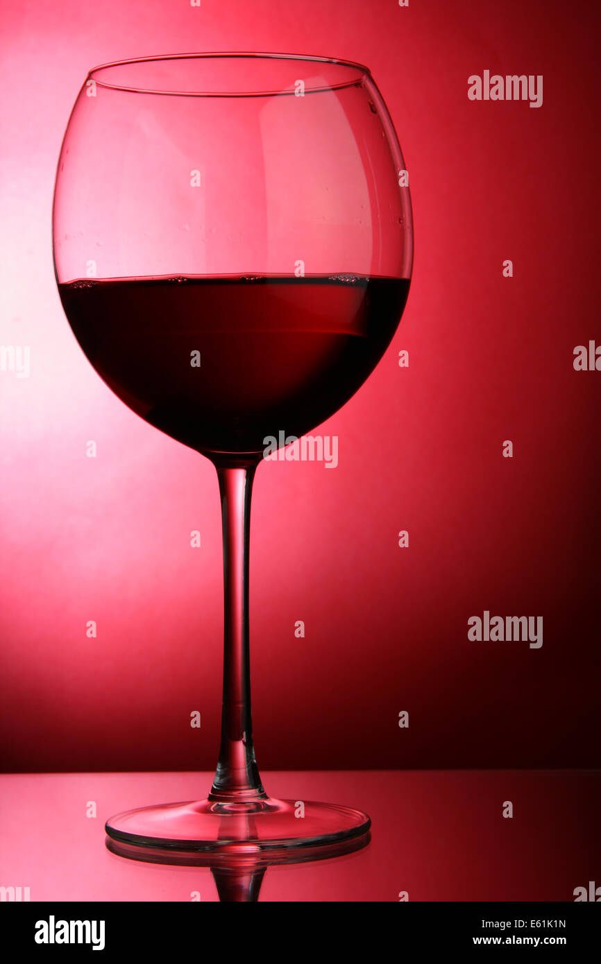 Glass of red wine close-up over red background Stock Photo - Alamy