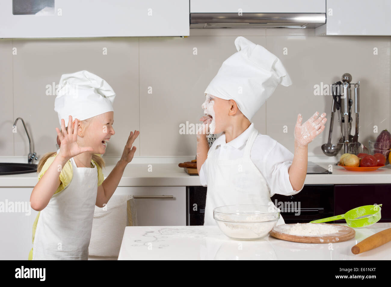 Two cute kids dressed up as chefs playing around in the kitchen Stock ...