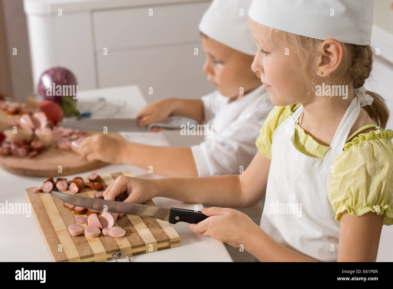 Two young children, a girl and boy, in chefs uniforms standing side by ...