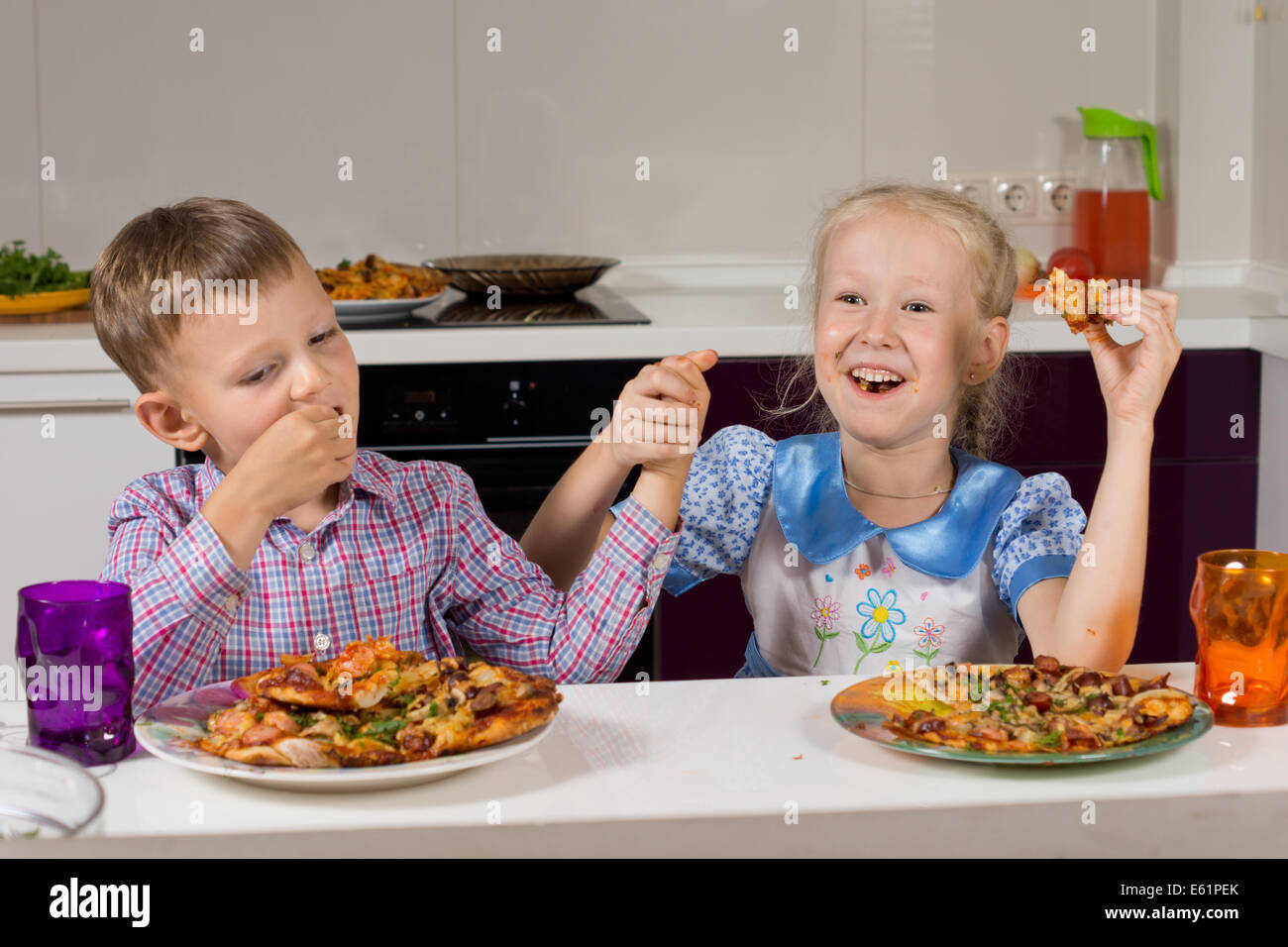 Two children celebrating eating their homemade pizza that they have ...