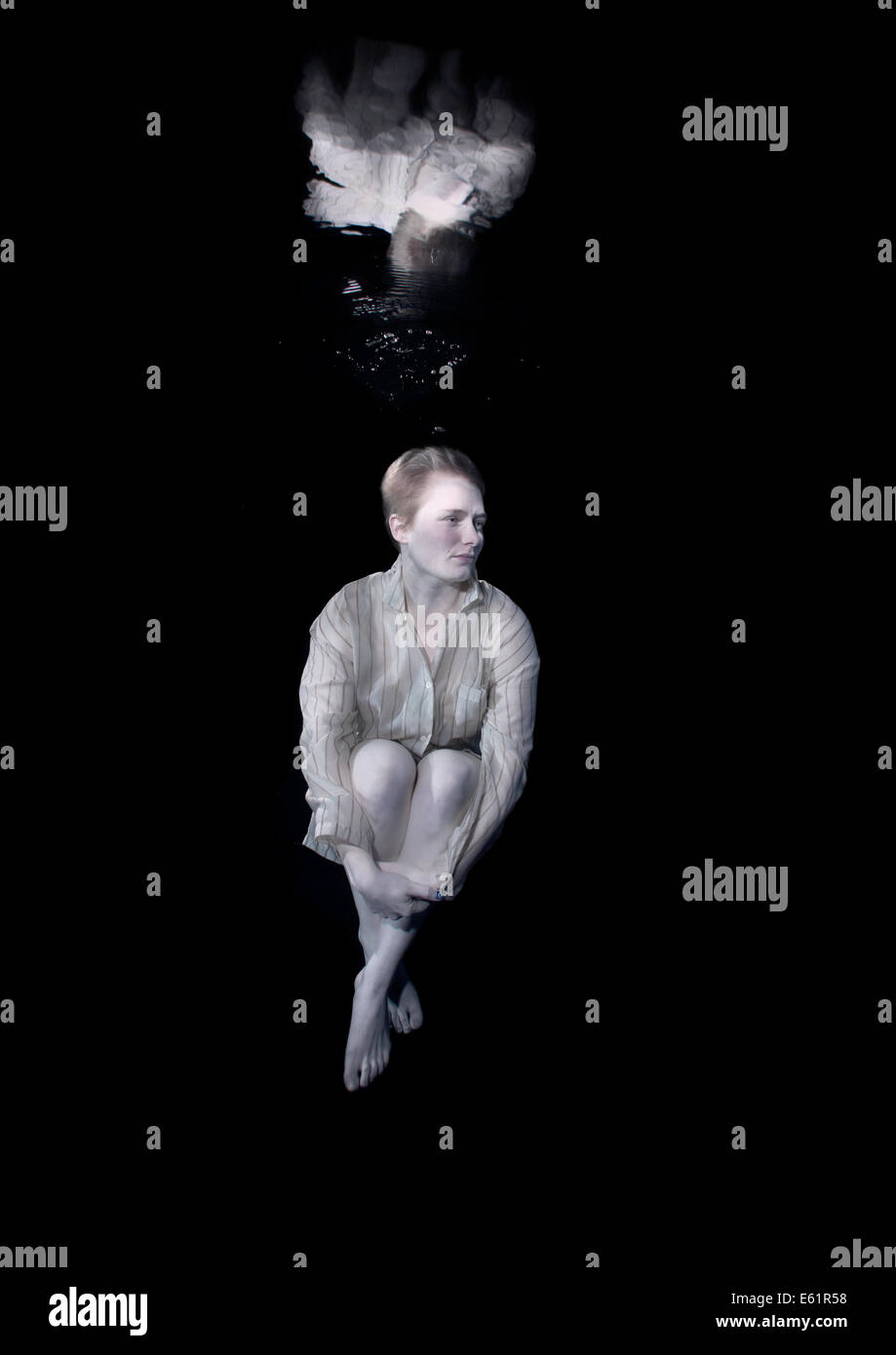 Underwater portrait of a woman looking thoughtful wearing a shirt and ...
