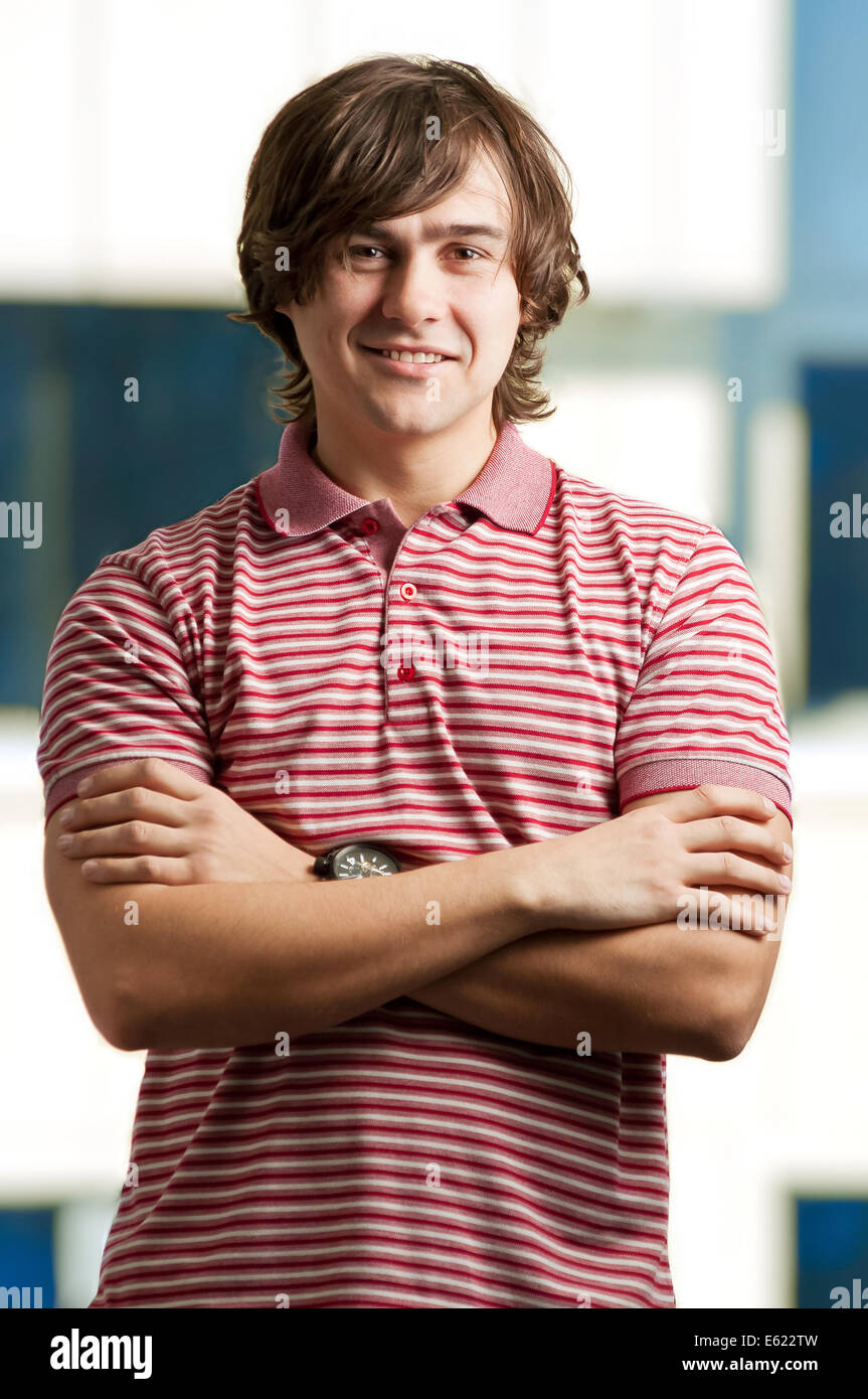 Portrait of a happy young man standing with folded hands Stock Photo ...