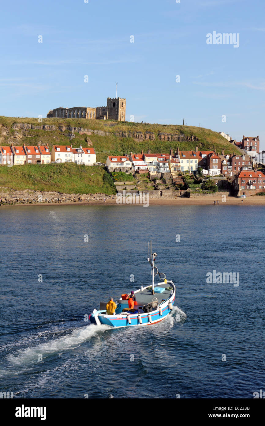 Fishing boat enters the harbour in the pretty coastal town of Whitby ...