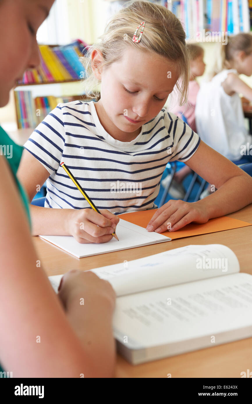 Elementary School Pupil Working At Desk In Classroom Stock Photo - Alamy