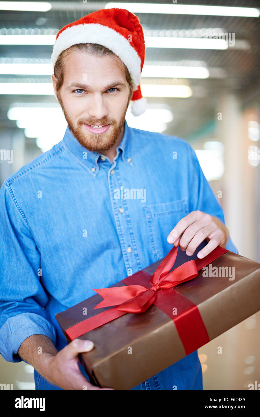 Portrait of a young man unpacking Christmas present Stock Photo - Alamy