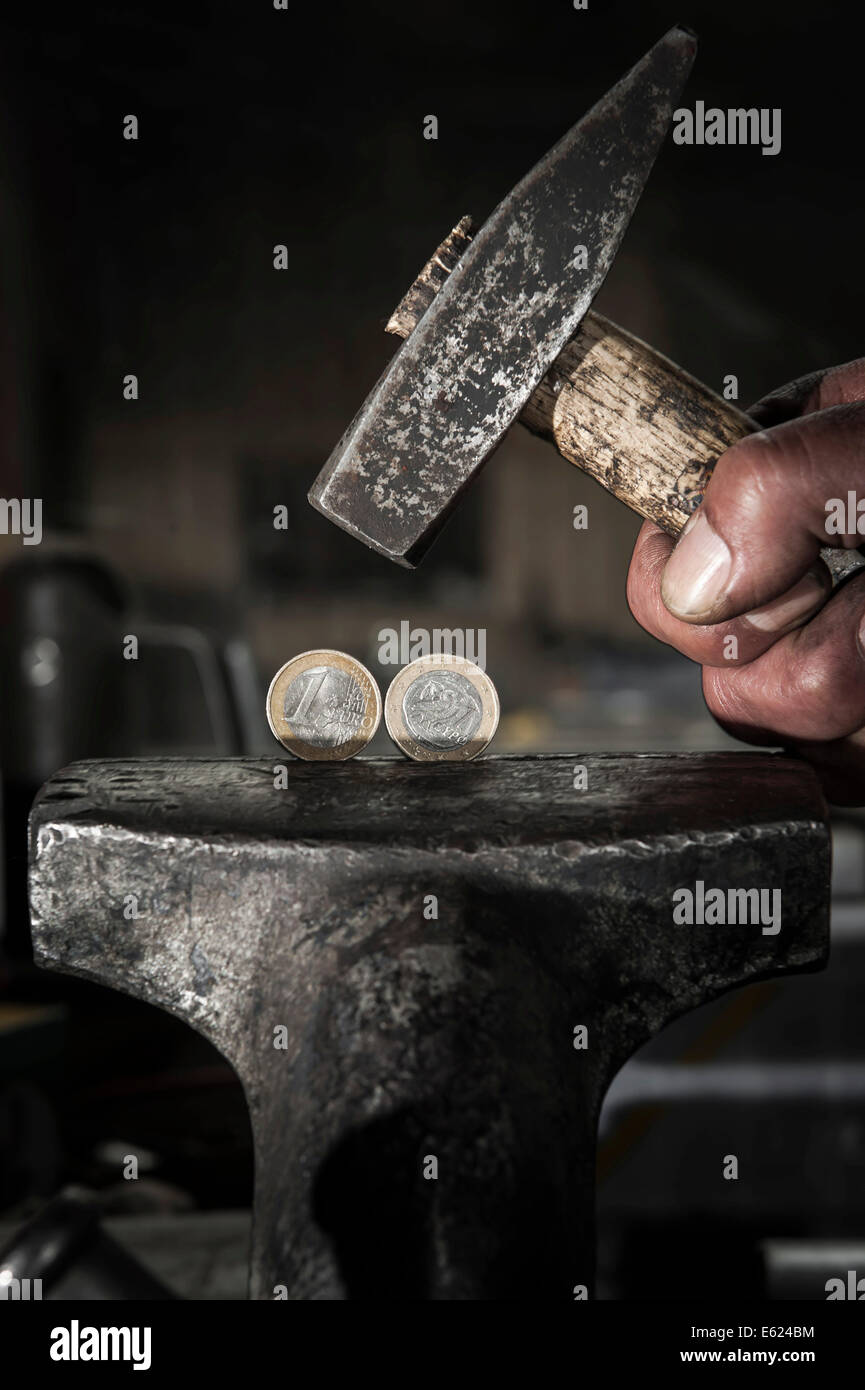 Greek euro coins under pressure in a vice and threatened by a hammer ...