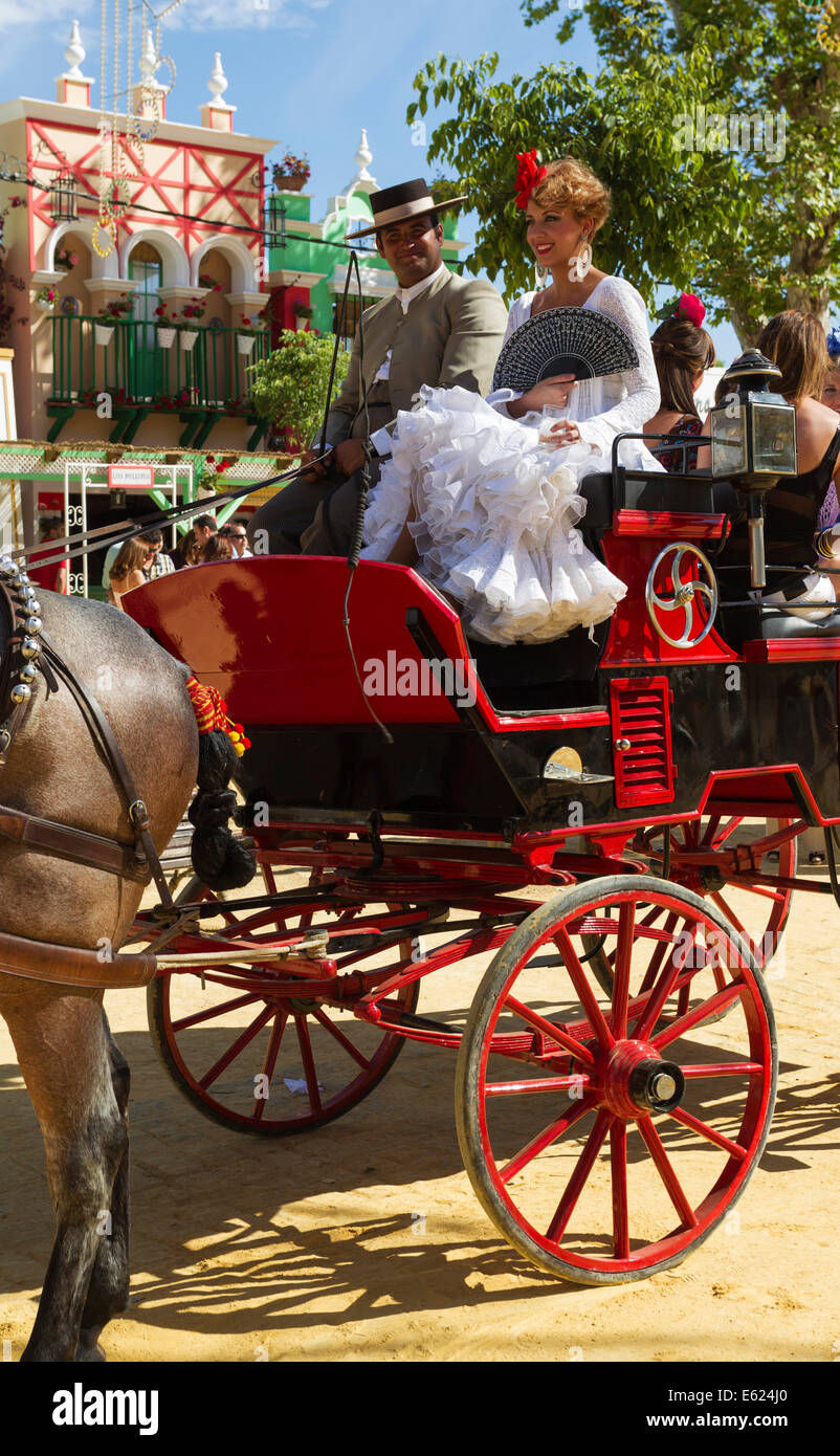 Dressed up coachman and young lady wearing a gypsy dress at the Feria ...
