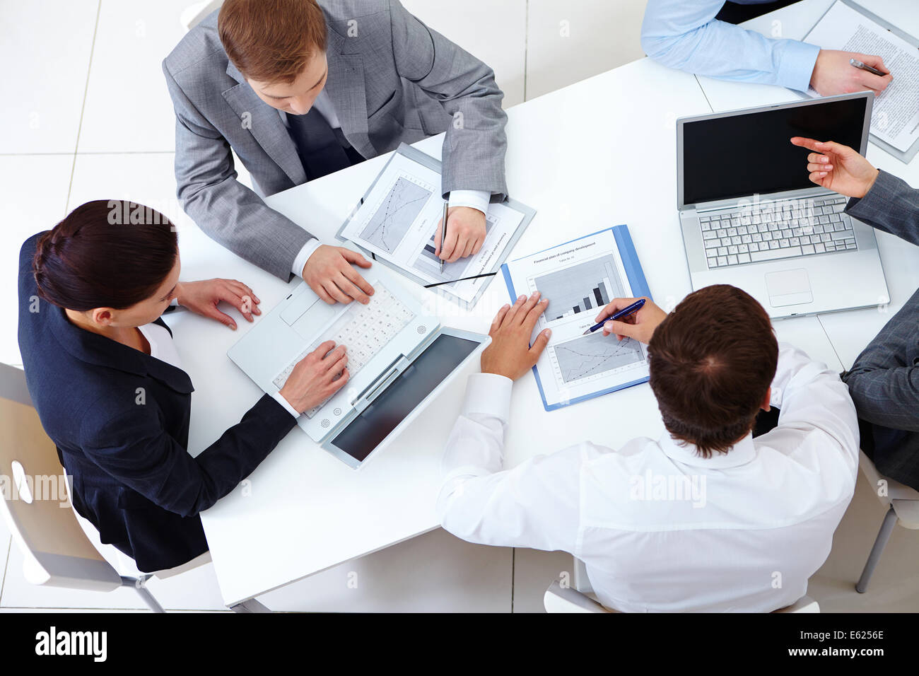 Above view of business team sitting around table and working Stock ...