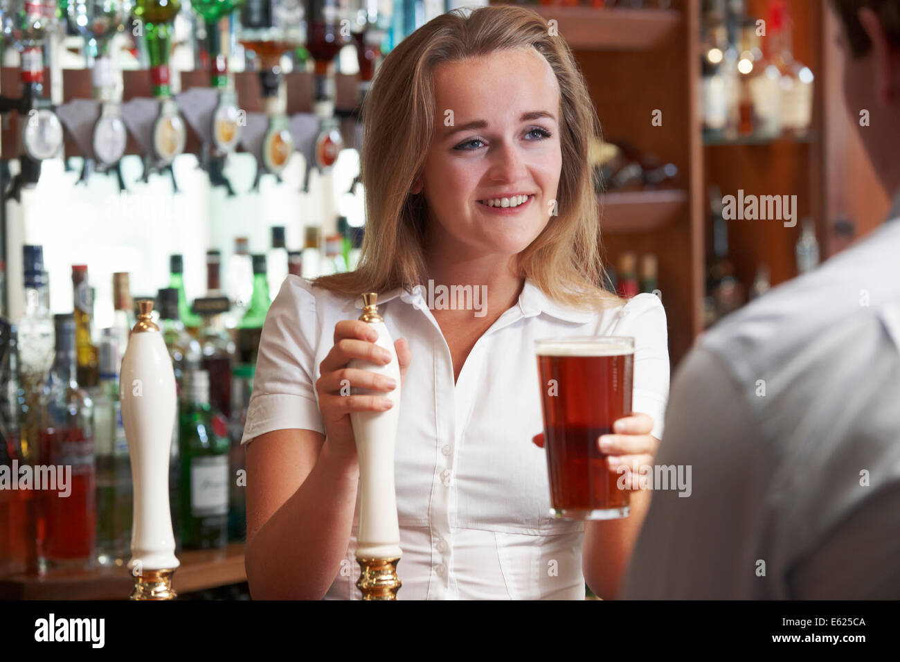 Female Bartender Serving Drink To Male Customer Stock Photo - Alamy