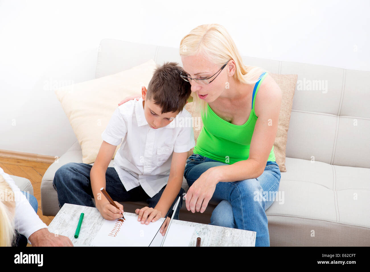Kids drawing with happy parents on the couch Stock Photo - Alamy