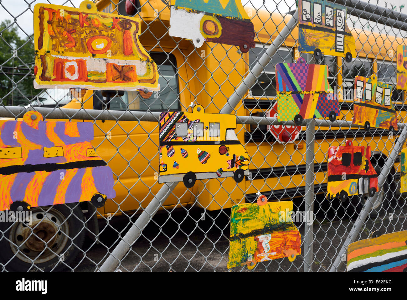 Yellow school bus with fence covered in paintings made by children in ...