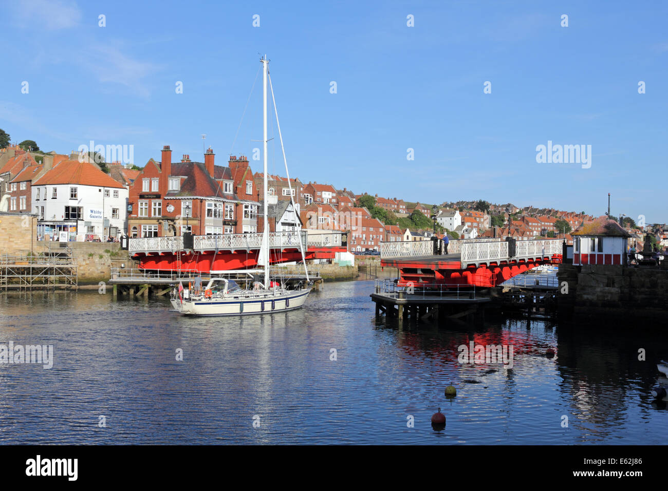 A yacht passes through the swing bridge in the harbour in coastal town ...