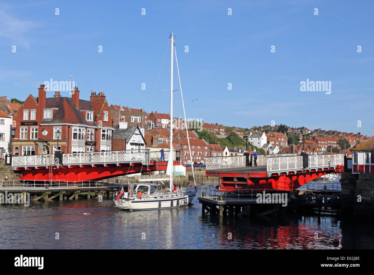 A yacht passes through the swing bridge in the harbour in coastal town ...