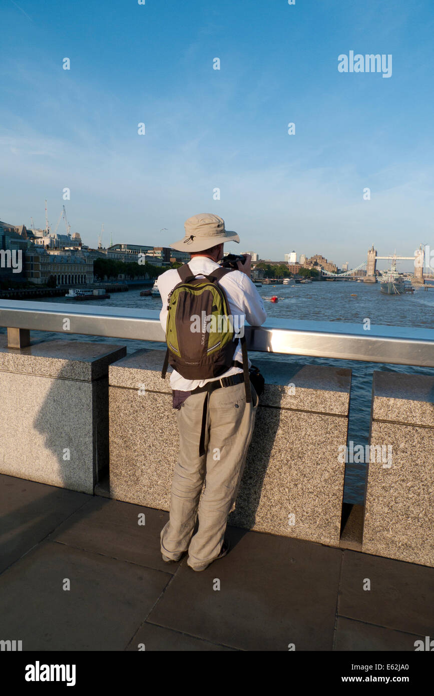 Rear view of man with rucksack standing on London Bridge looking at the ...