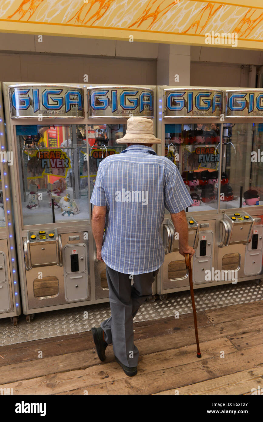 Mature man 50s or 60s standing with a stick in an amusement arcade in ...