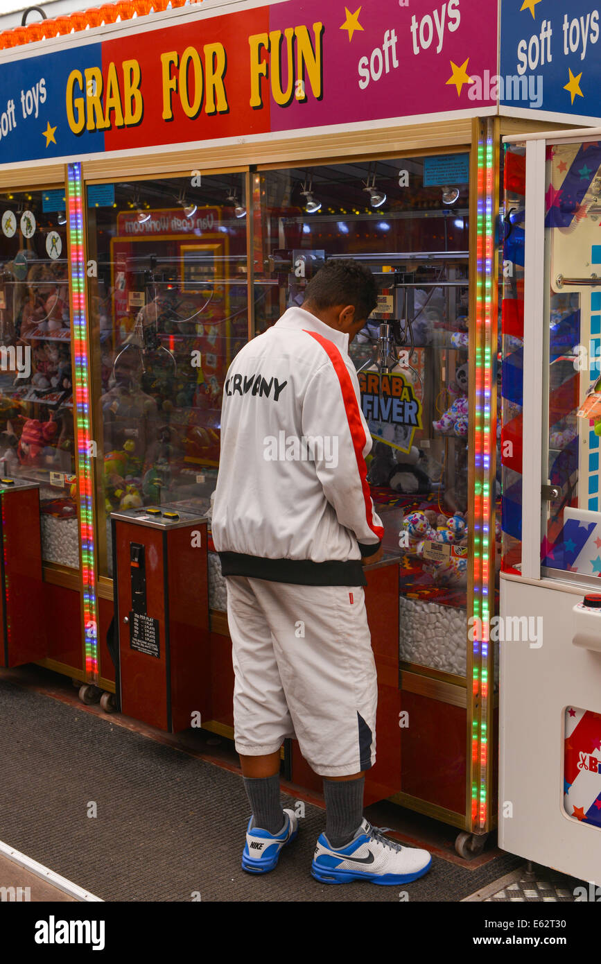 Black man in his twenties playing a grab machine at the amusement ...