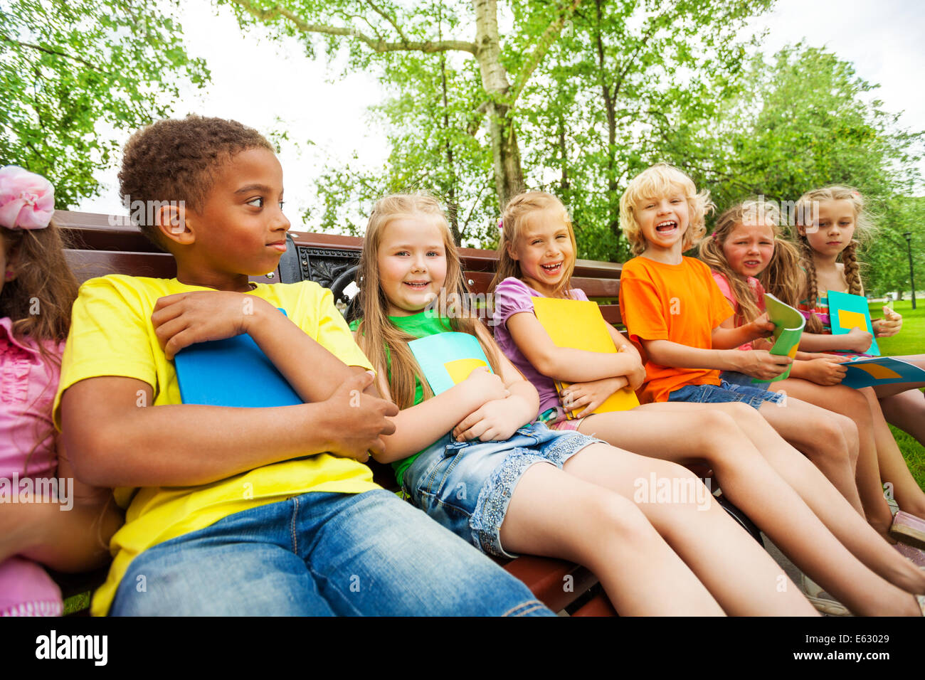 Happy school kids on bench sit in row together Stock Photo - Alamy