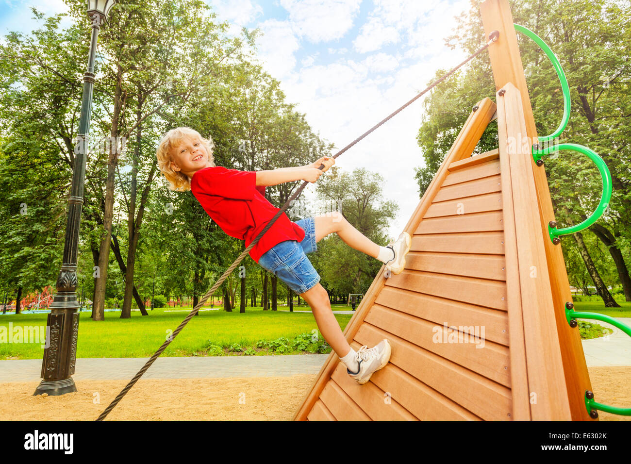 Positive boy climbs on wooden construction Stock Photo - Alamy