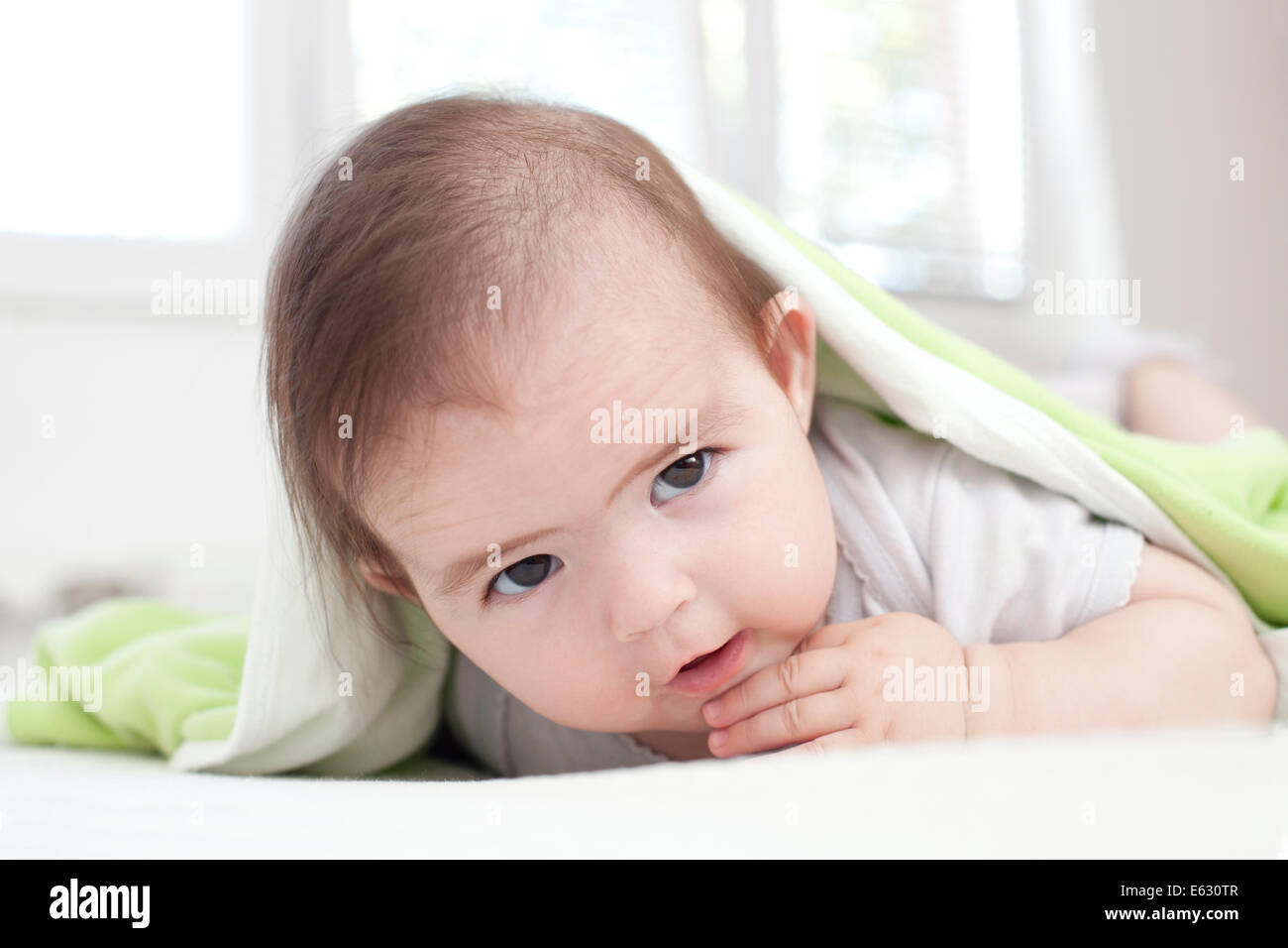 Baby girl is hiding under the white and green blanket Stock Photo - Alamy