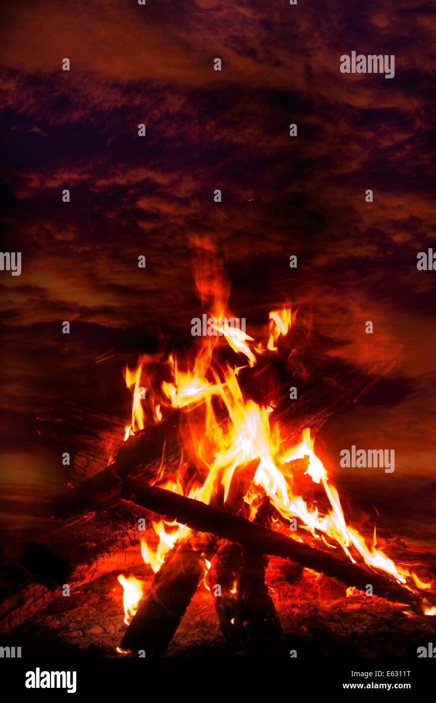 A wood fire burns, the flames reaching up into a dramatic sky Stock ...