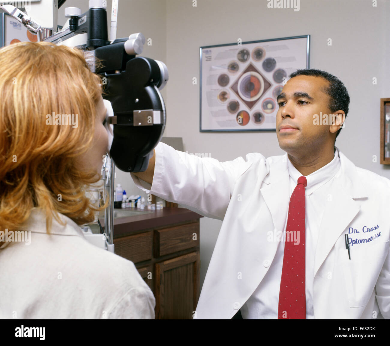 AFRICAN AMERICAN OPTOMETRIST EXAMINING WOMAN'S EYES WITH PHOROPTER ...