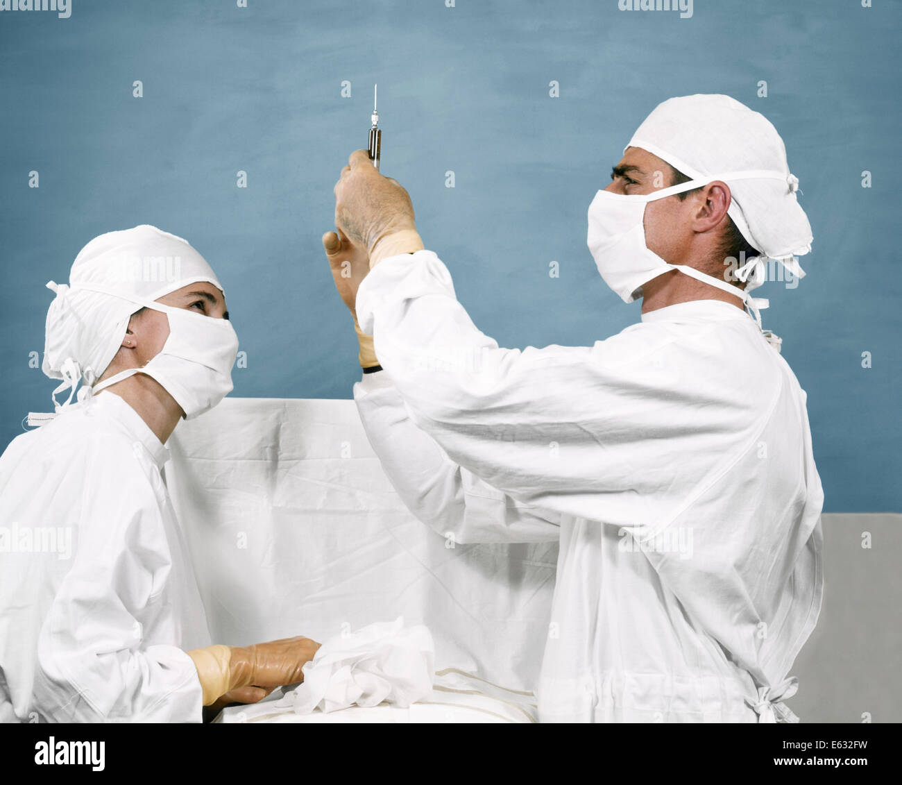 1960s Man Doctor Woman Nurse Wearing White Masks Caps Gowns Sterile
