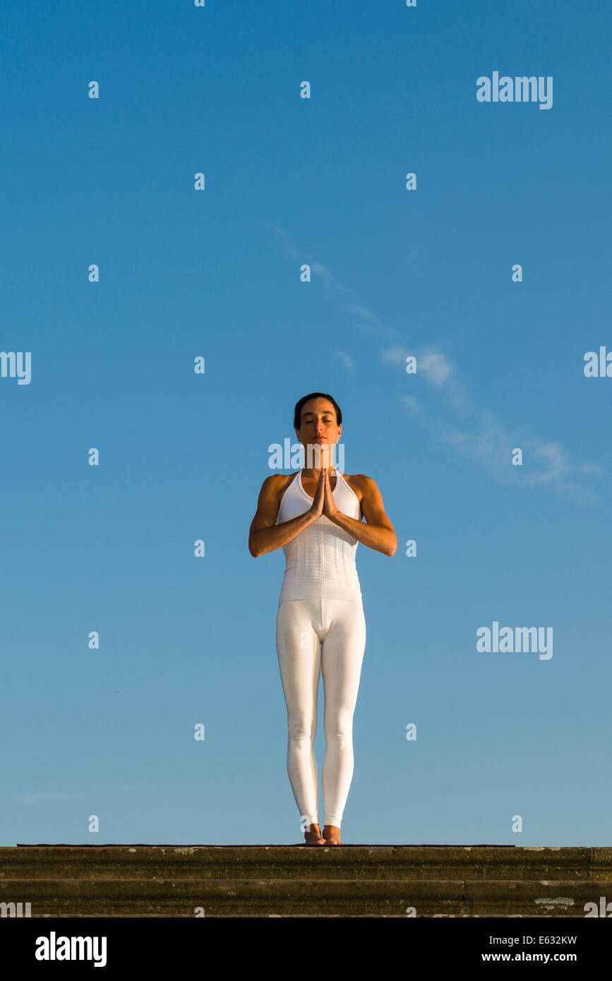 Young woman practising Hatha yoga, outdoors, showing the pose Tadasana ...