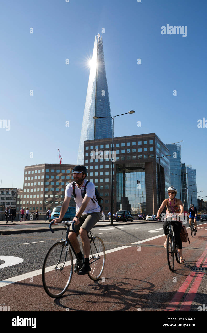 Morning commuters cycling over London Bridge with The Shard behind ...