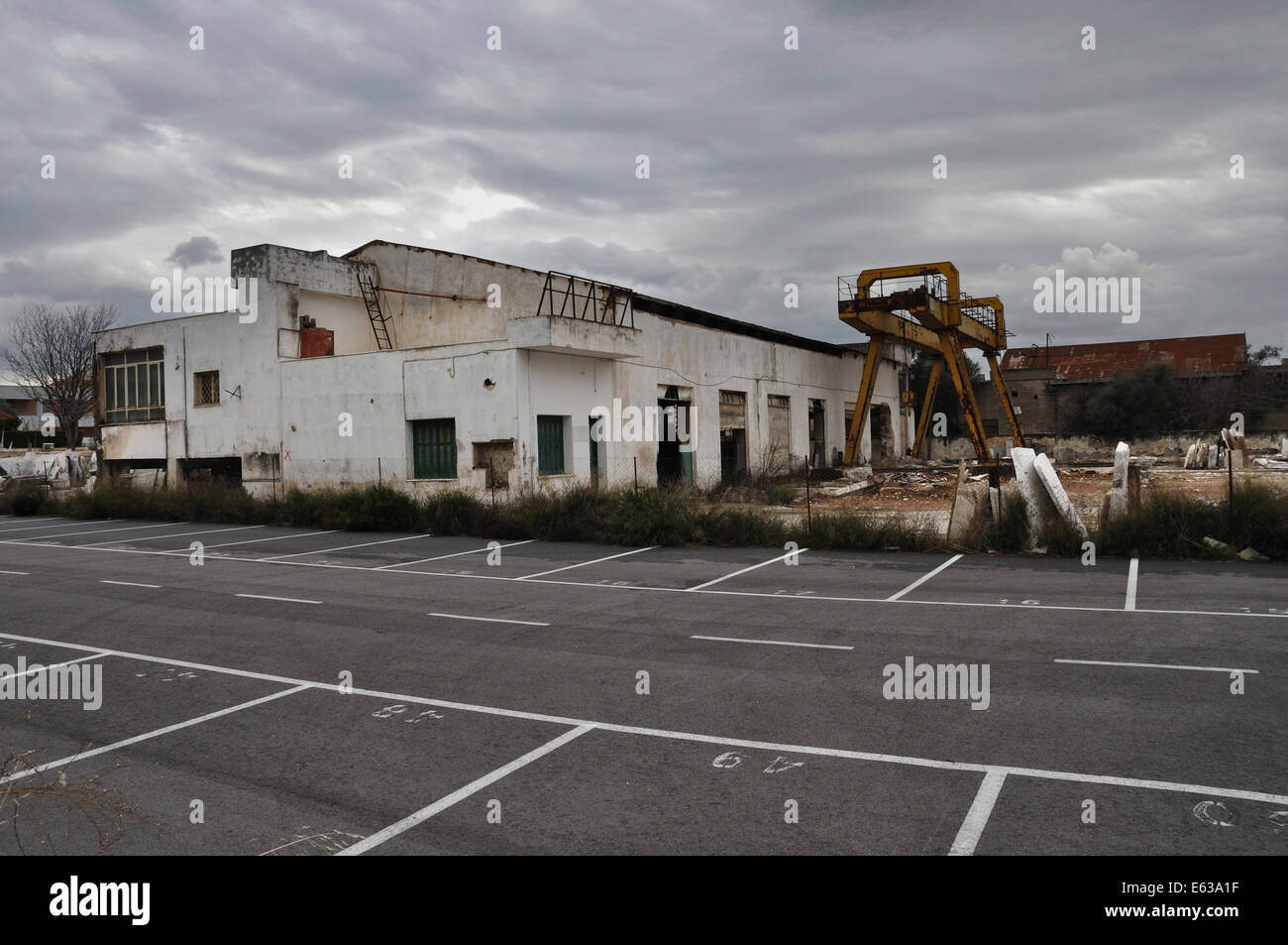 Abandoned factory exterior and empty parking lot under cloudy winter ...