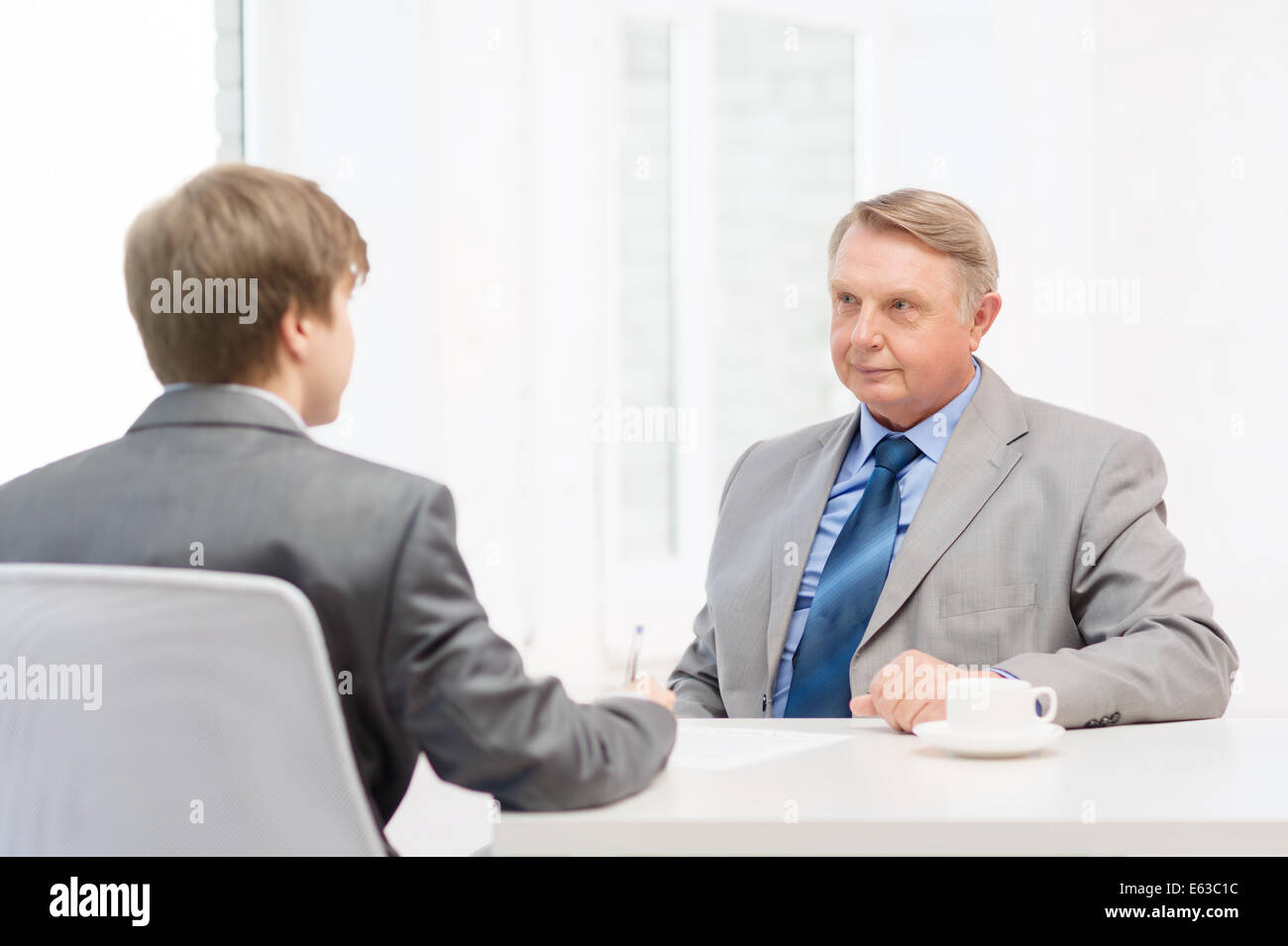 older man and young man signing papers in office Stock Photo - Alamy