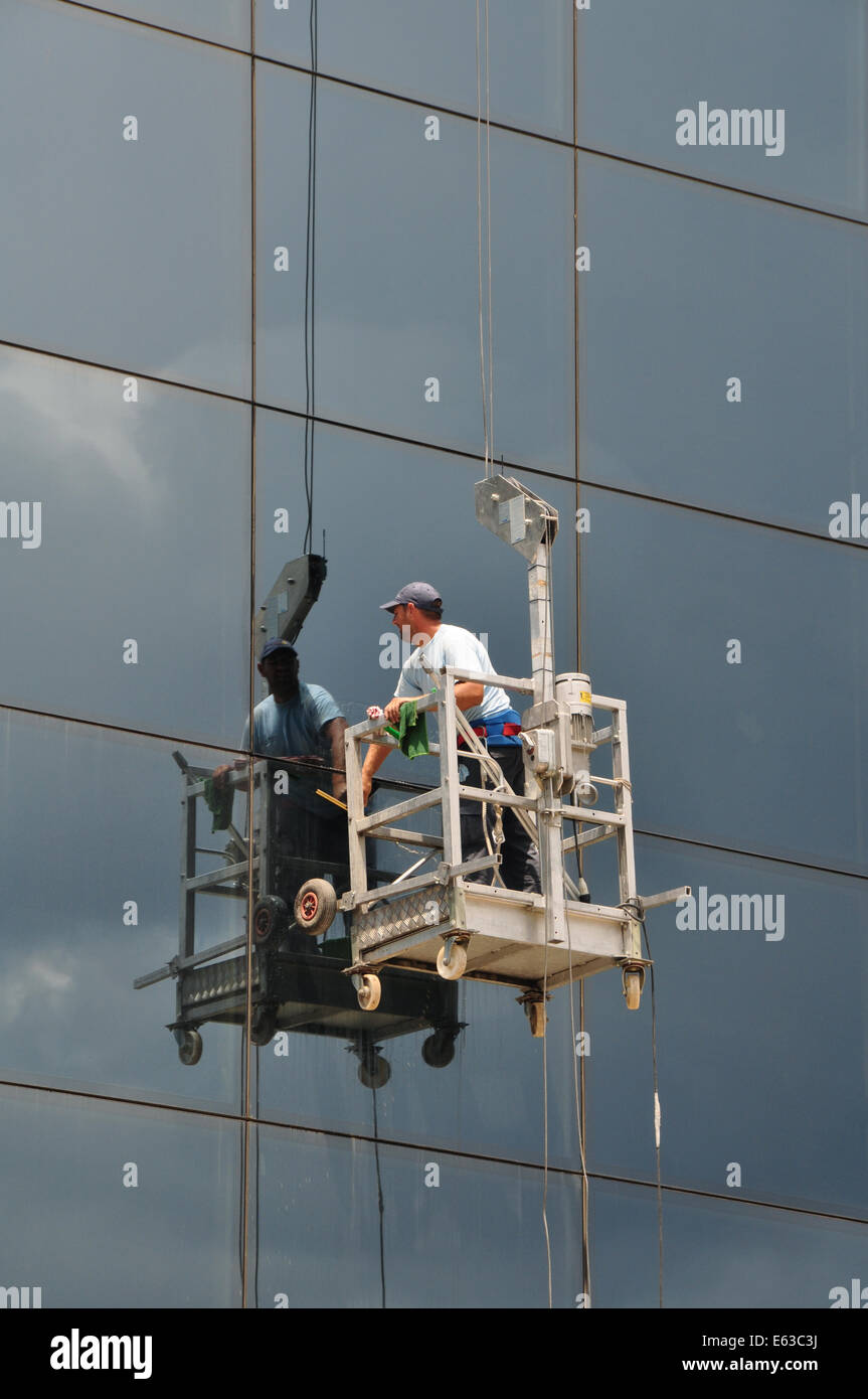Man cleaning the windows of high rise building glass facade. Working at ...