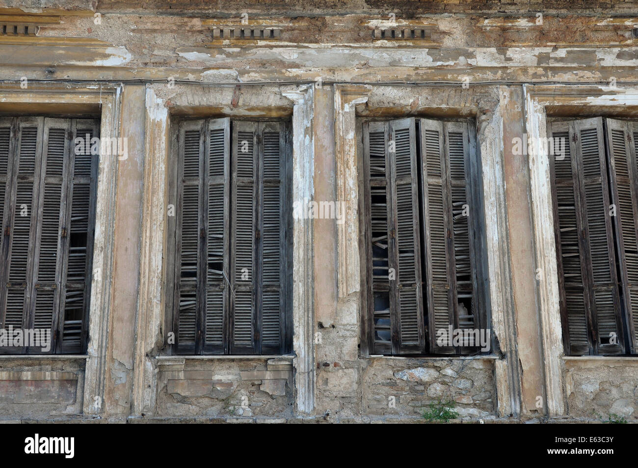Broken wooden window shutters and chipped wall of a decayed building ...