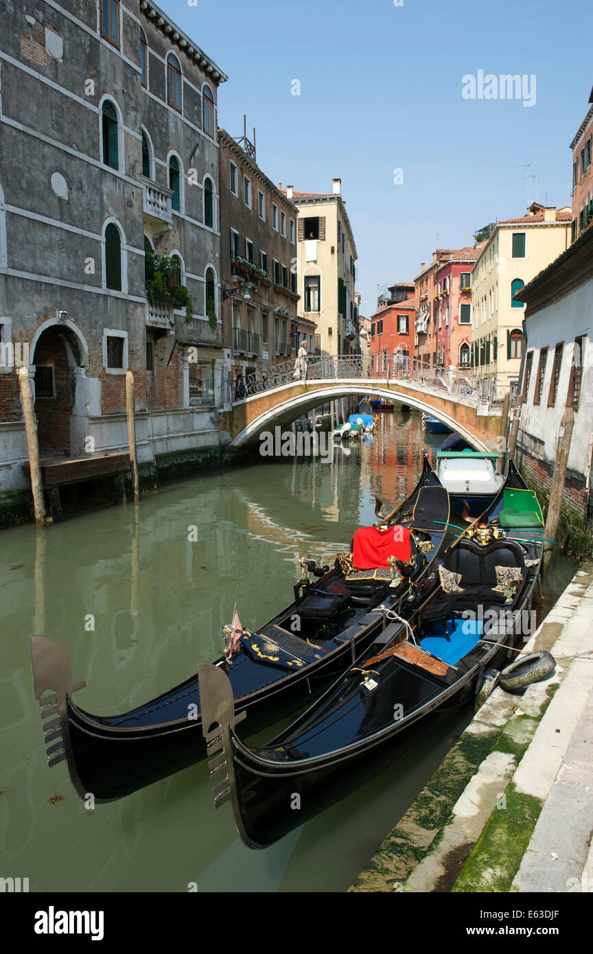 Traditional Venetian gondolas docked on small canal in Venice Italy ...