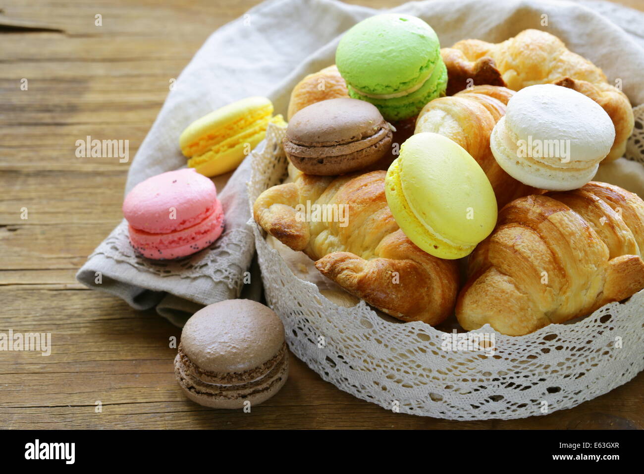 traditional French pastries croissants and macaroons in a lace basket ...