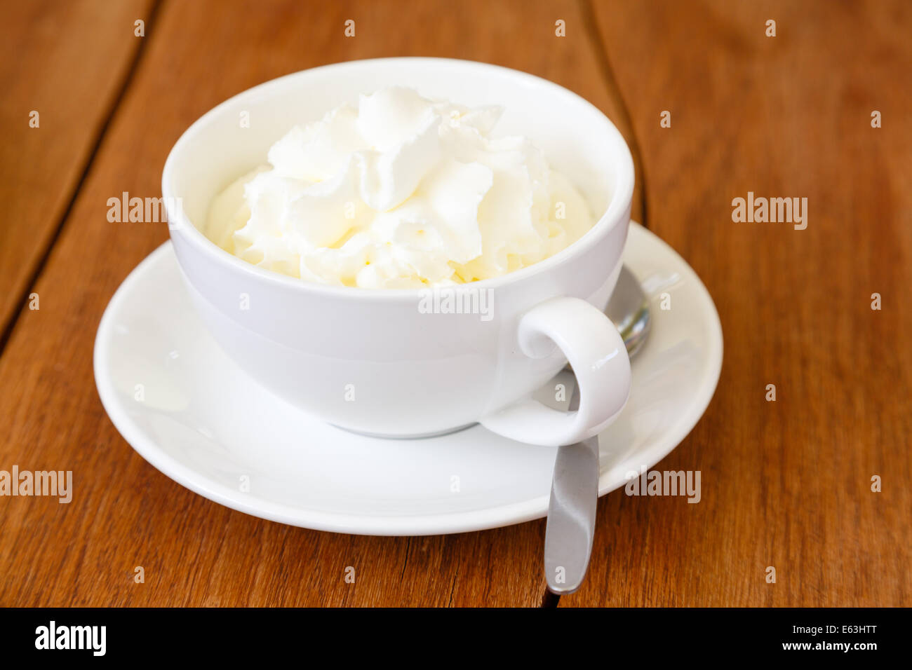 Cup of whipped cream with spoon on wooden table Stock Photo - Alamy