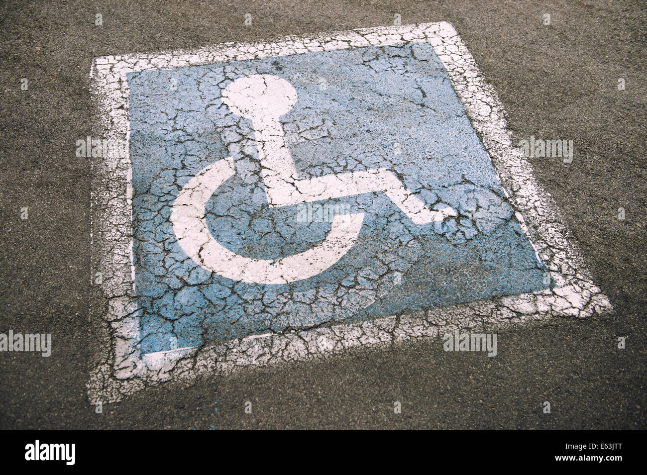 Weathered disabled parking sign in textured paint on the parking lot ...
