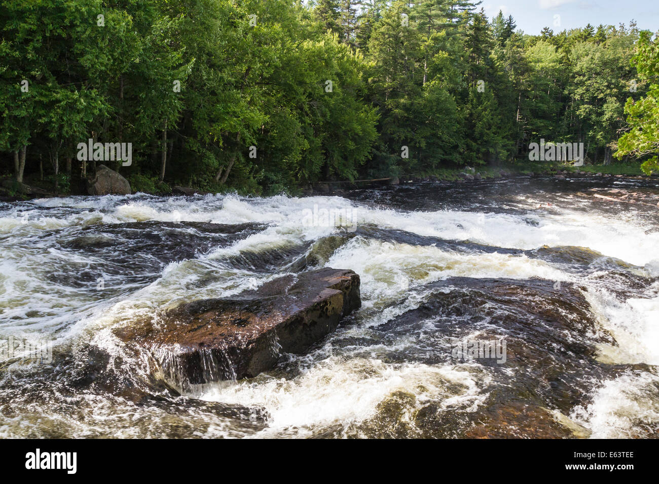 A boulder in the middle of the Raquette River amidst the rapids of ...