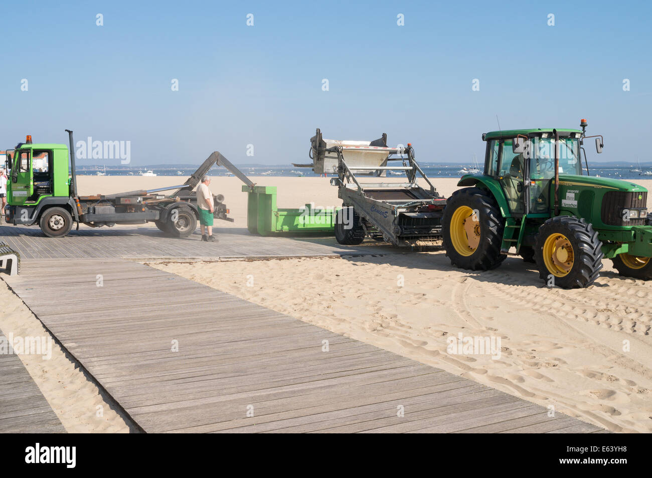 Workmen with tractor, truck and Canicas beach cleaning machine Arcachon ...