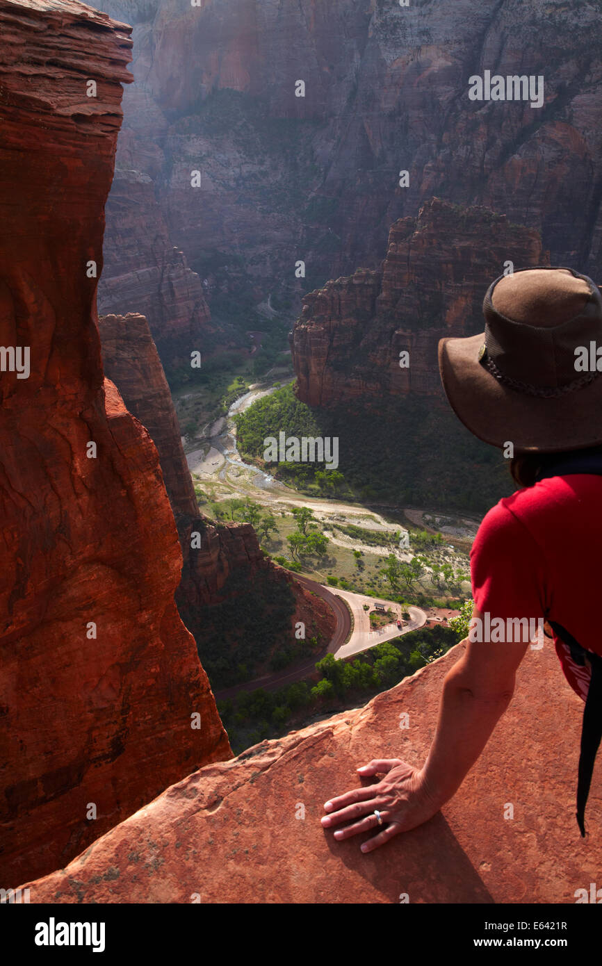 Hiker looking off sheer cliff into Zion Canyon from Scout Lookout ...