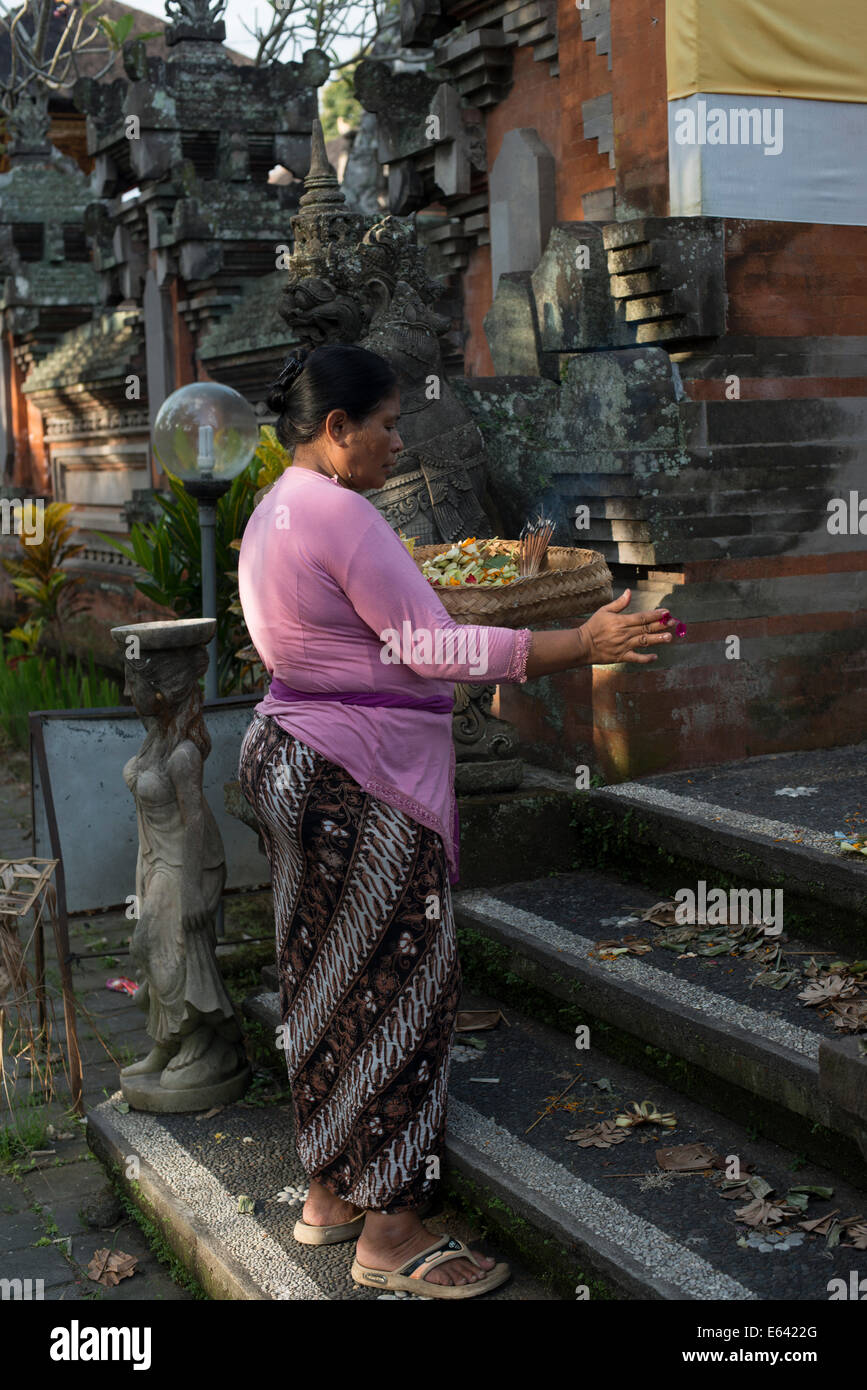 Lady placing offerings at the entrance of a building for good fortune ...