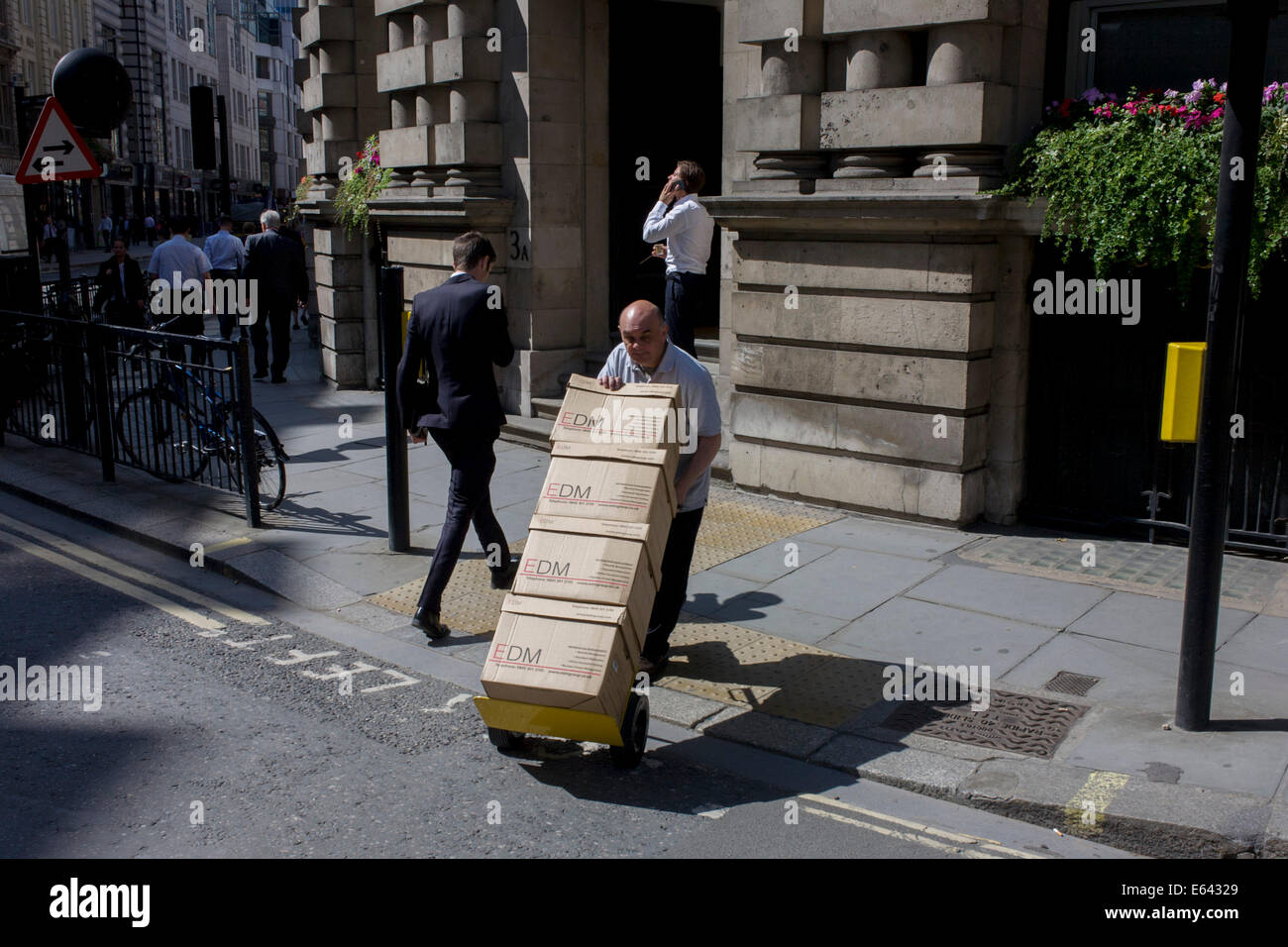 A middle-aged man carefully delivers boxes across a road junction in ...