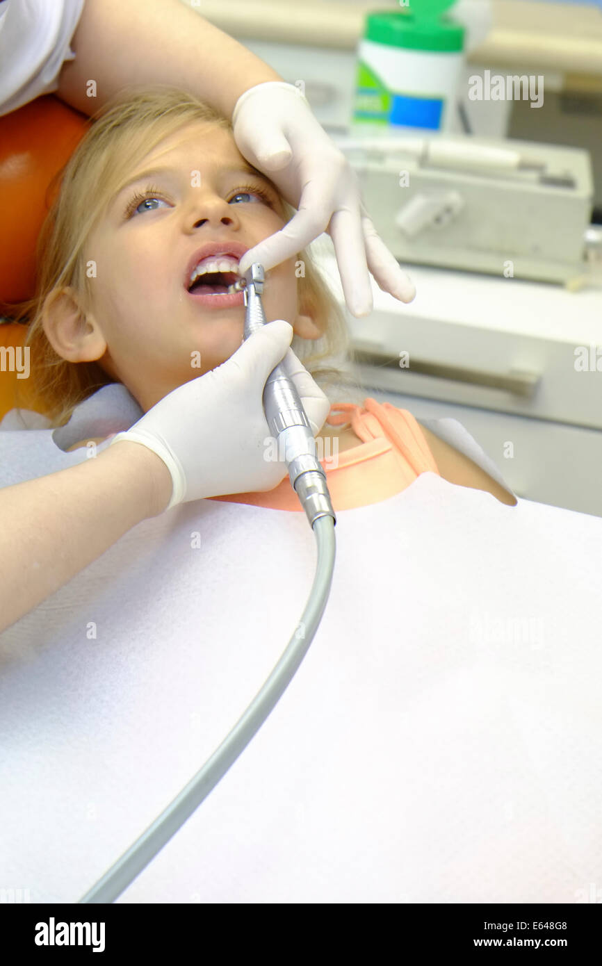 Young girl has her teeth cleaned by a dental hygienist at the dentist ...
