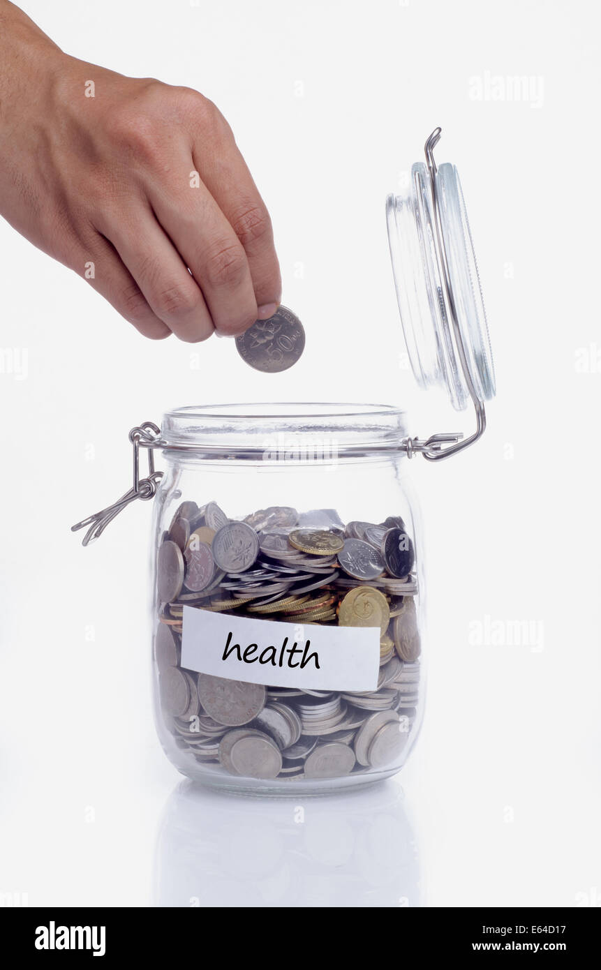 Hand putting a coin into glass jars with 'health' text Stock Photo - Alamy