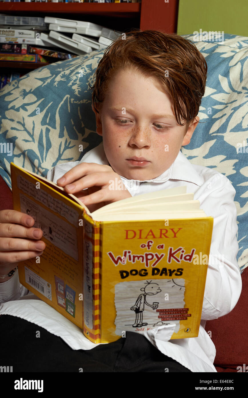 Young boy at home after school reading a book Stock Photo - Alamy