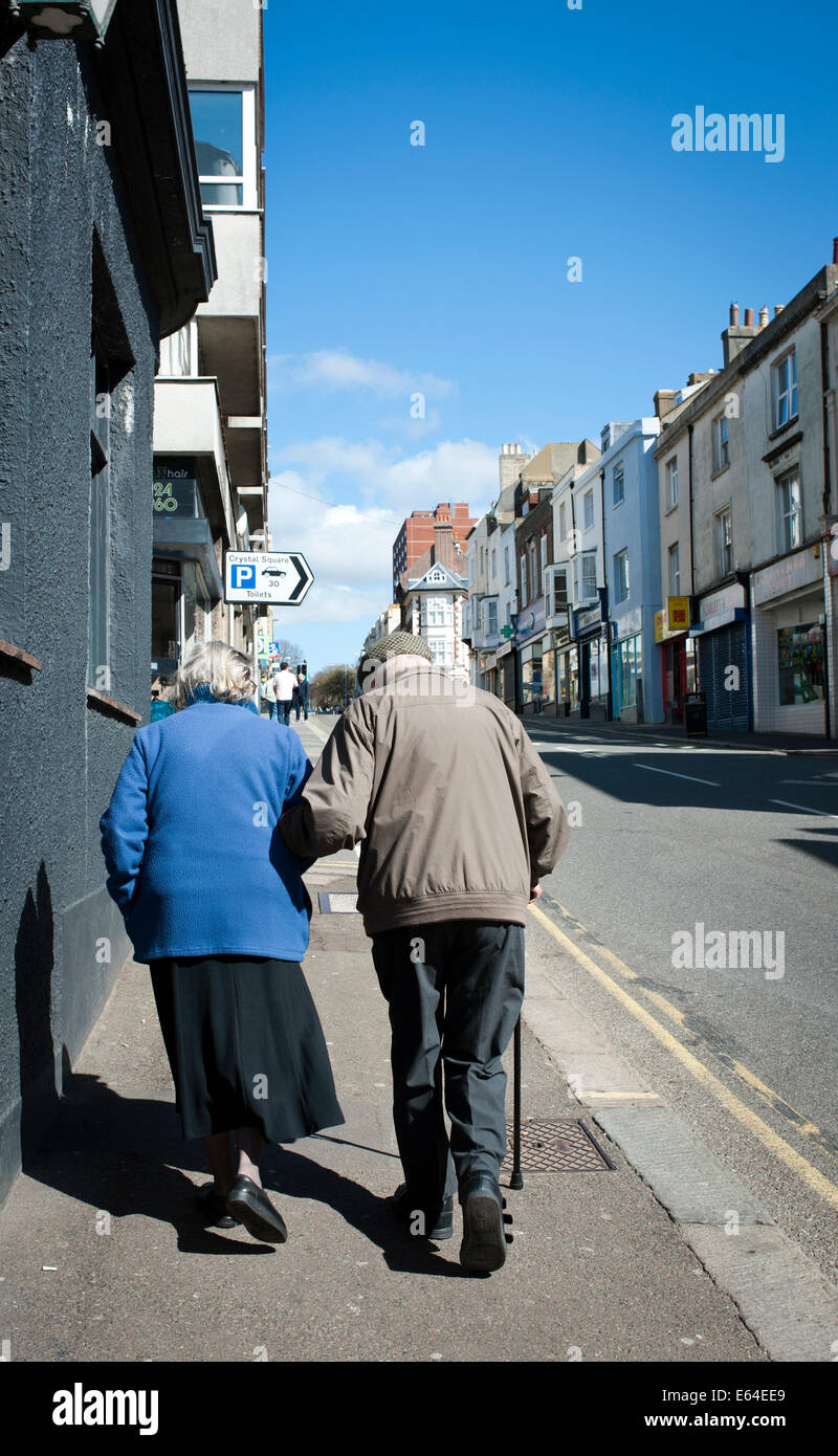 Two senior citizens walking along the High Street Stock Photo - Alamy