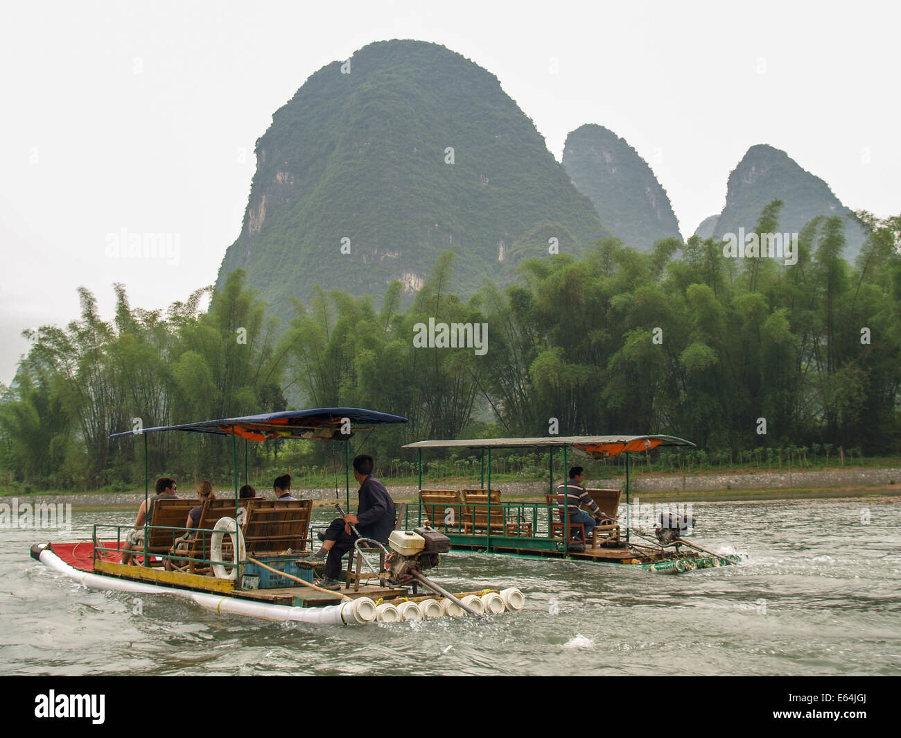 Small boats ferry tourists down Li River in China against tall bamboo ...